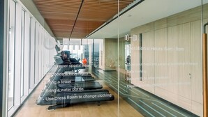 Academia moderna com ripas de madeira no teto, equipamentos de cardio e armários.