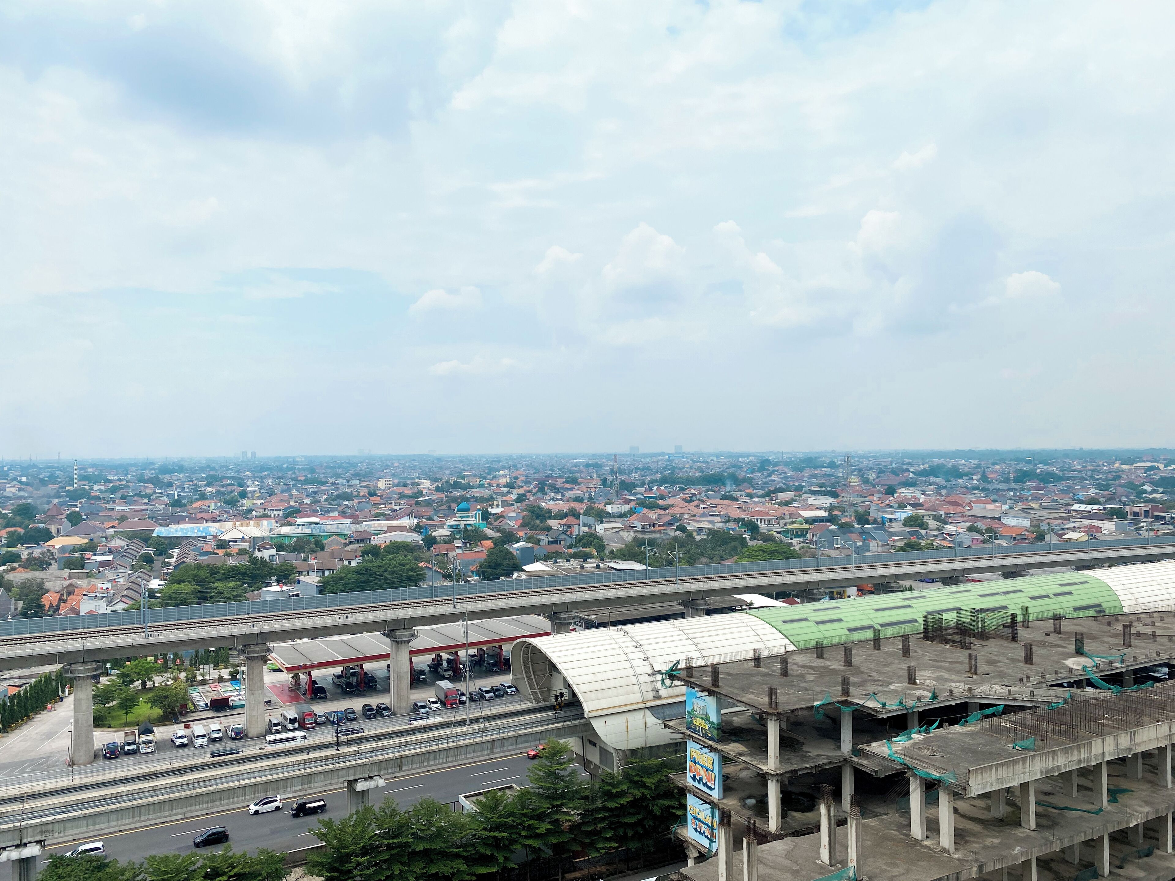 Paisagem urbana com viaduto, estacionamento e edifício com telhado verde.