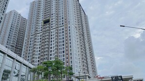 Um edifício residencial alto com várias varandas, fachada de vidro moderna e uma placa indicando uma universidade próxima.