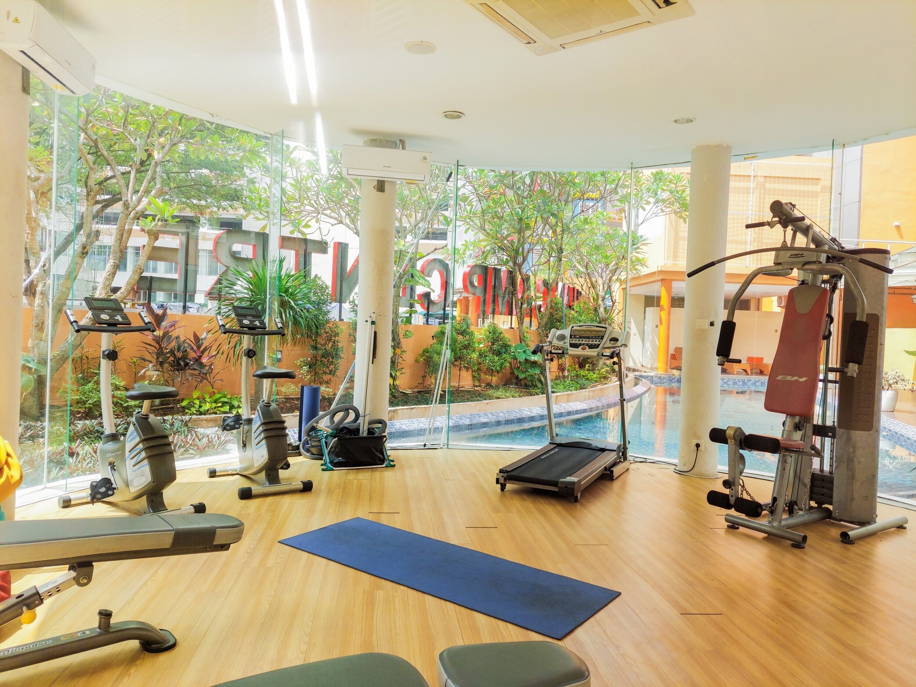 Uma academia com equipamentos de cardio, esteira e aparelhos de musculação.