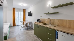 Uma cozinha moderna com bancada de madeira, armários verdes e lava-louças embutida.