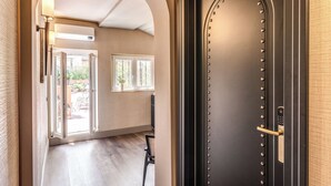 Entrada de um hotel com porta escura, corredor que leva a um quarto e vista para a área externa.