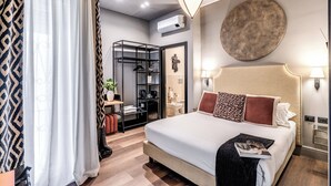 Quarto de hotel moderno com uma cama grande, um guarda-roupa, uma mesa de trabalho com cadeira e uma decoração circular na parede.