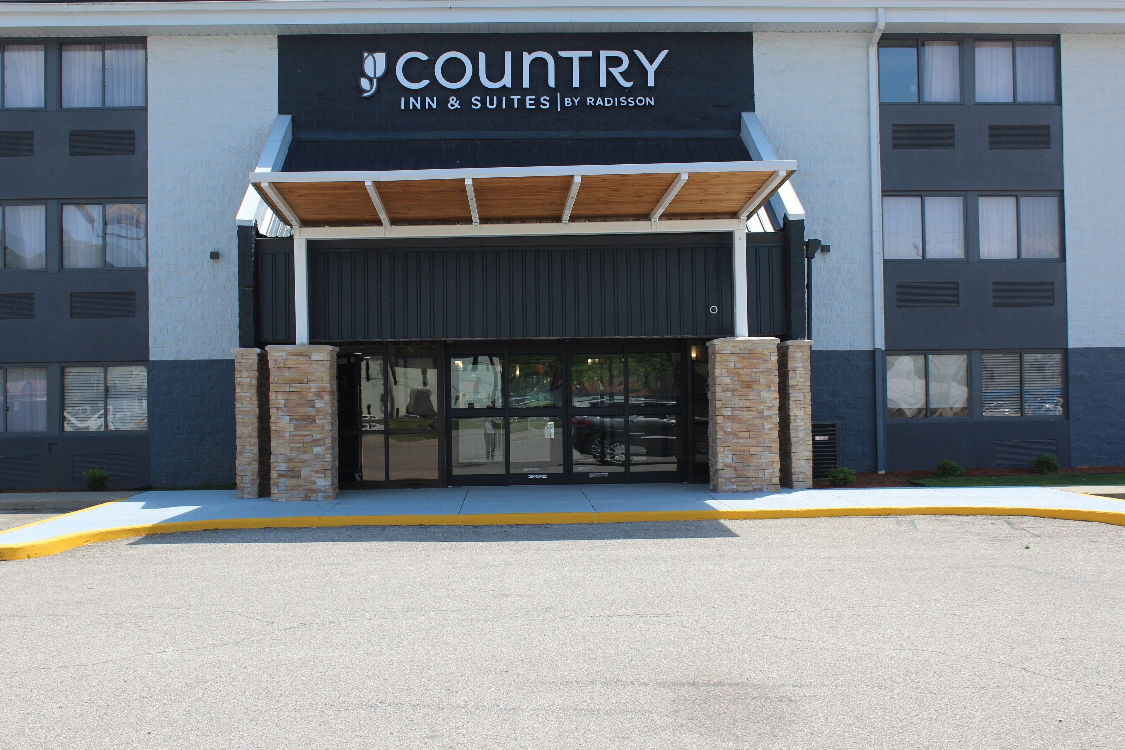 Edifício do Country Inn & Suites by Radisson com fachada moderna, ampla entrada de vidro e galeria coberta.