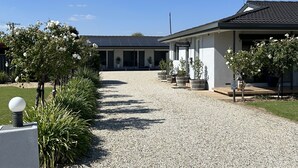 Edifício com área de recepção, caminho de brita e plantas em vasos.