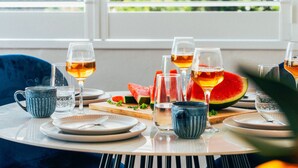 Uma mesa de jantar posta com pratos, copos e uma melancia como peça central.
