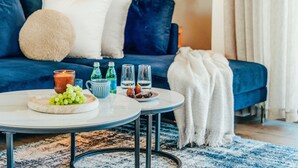 Uma sala de estar moderna com um sofá azul, uma mesa de centro redonda e um cobertor branco.