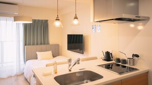 Quarto de hotel moderno com cama, mesa de cabeceira, pia e televisão de tela plana.