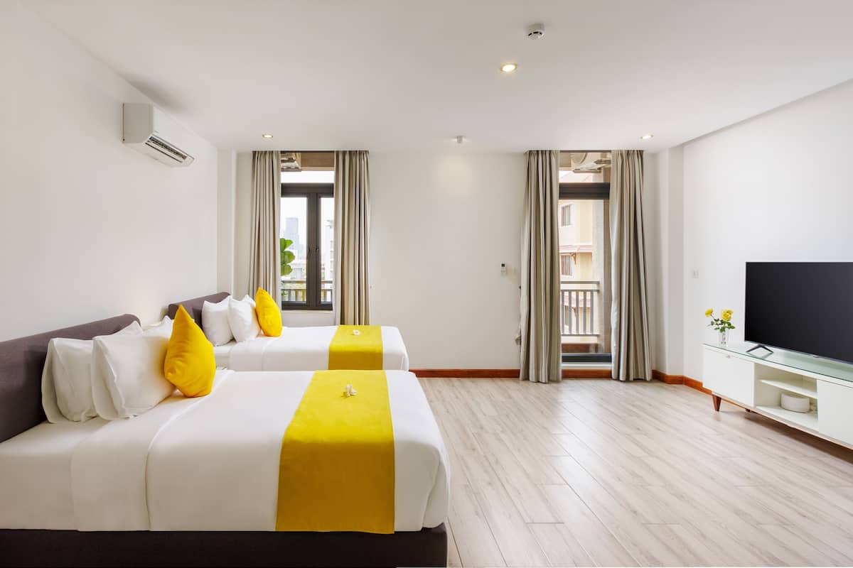 Quarto de hotel com duas camas, televisão e vista para a varanda.