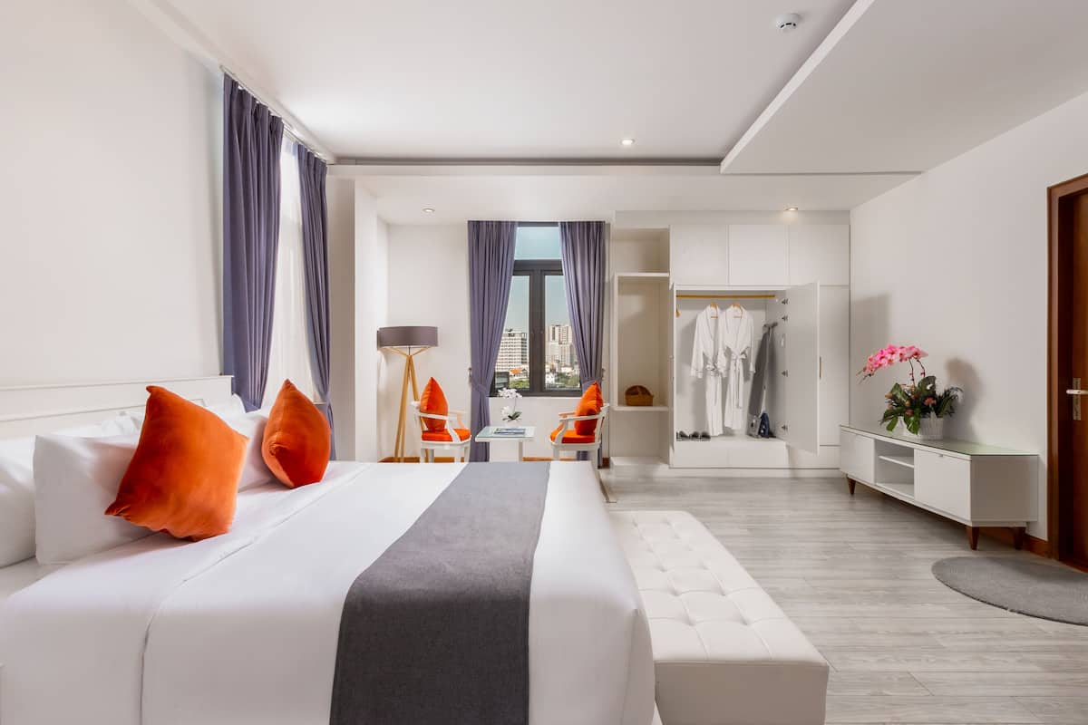 Quarto de hotel moderno com uma cama grande, uma escrivaninha e um closet espaçoso.