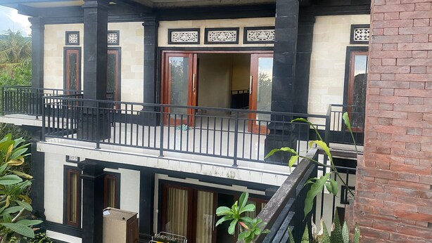 Um edifício de dois andares com varanda, janelas amplas e molduras decorativas.