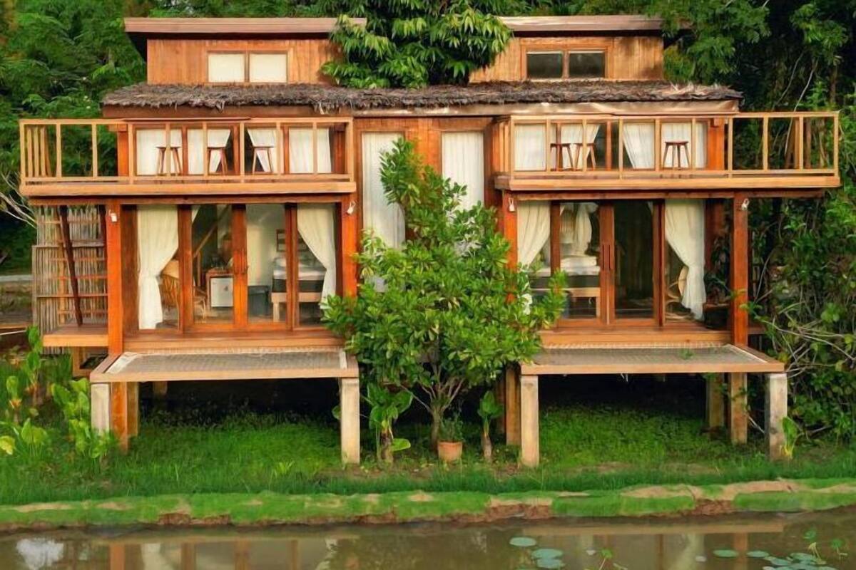 Uma casa de madeira com dois andares, janelas amplas e uma varanda.