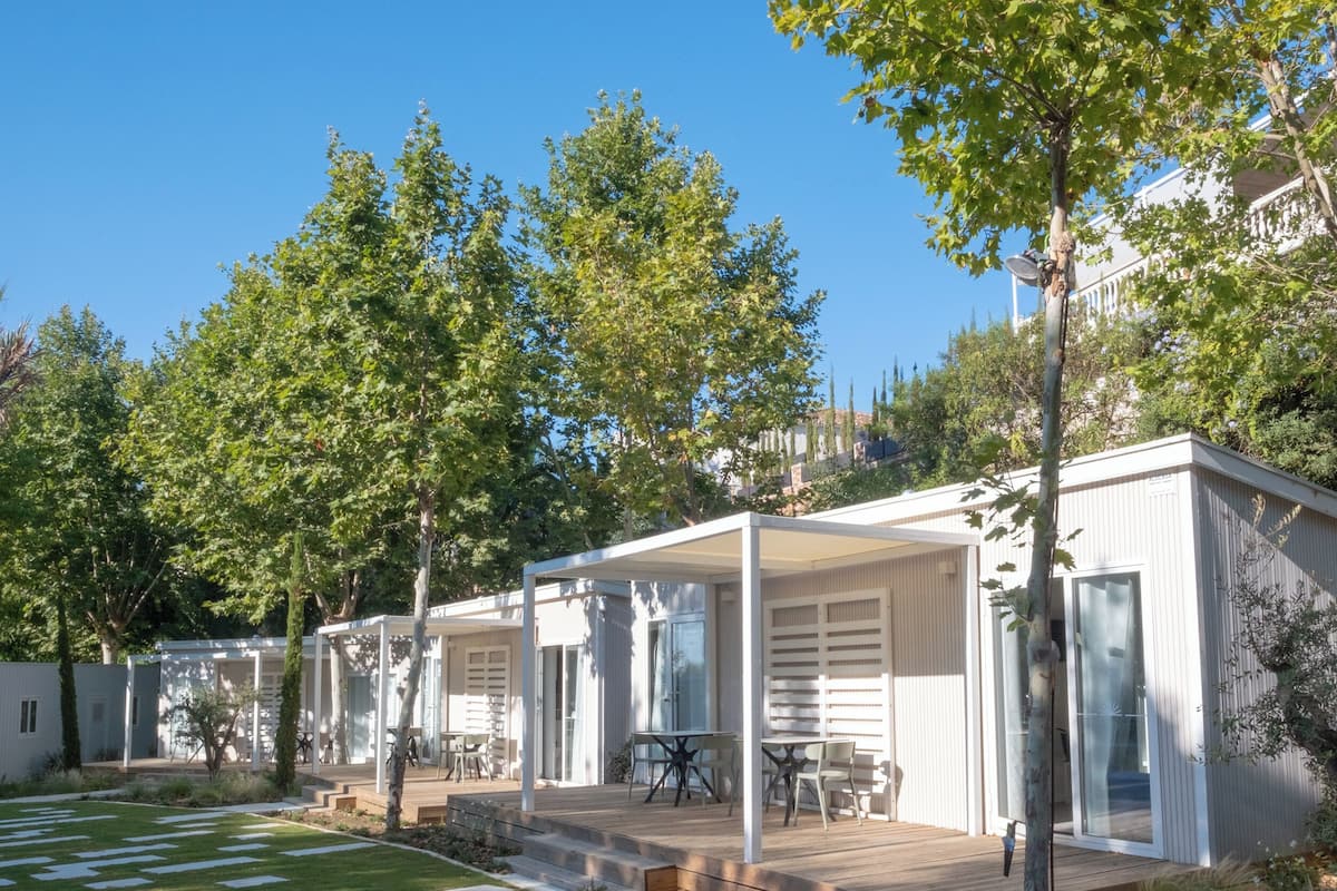 Uma área de varanda externa moderna com gramado quadriculado, deck de madeira e mobiliário para área externa.