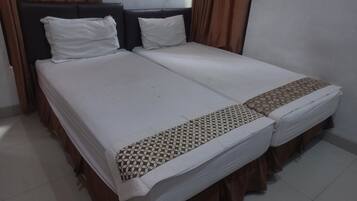 Uma cama de casal com cabeceira, roupa de cama branca e um corredor estampado.