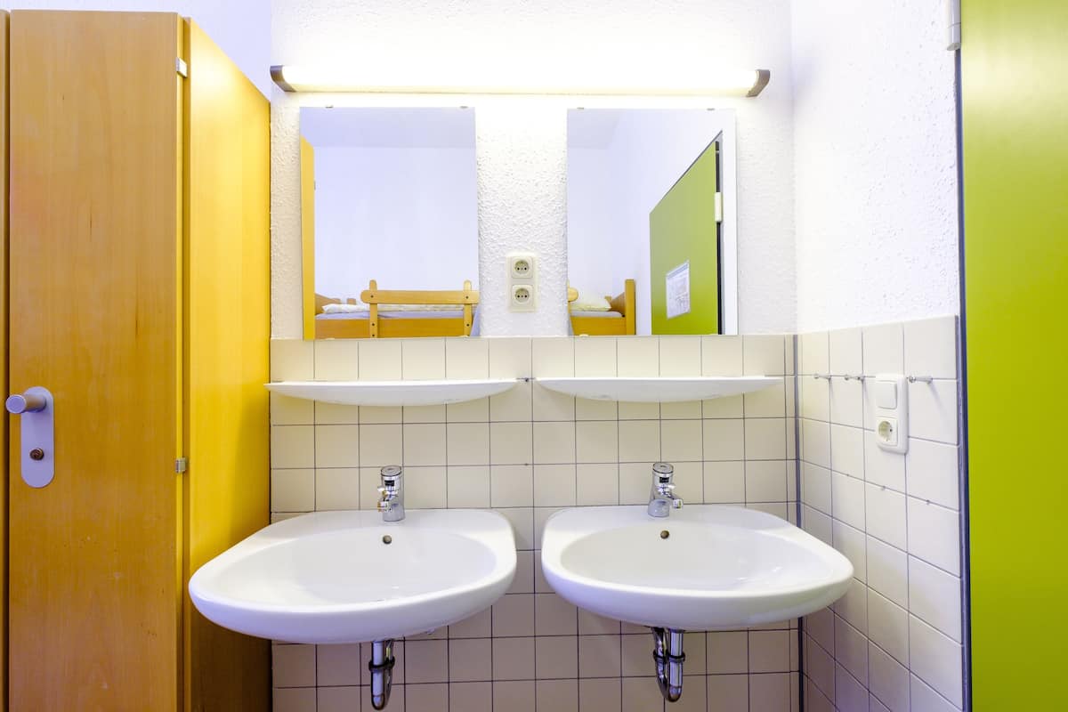Casa de banho com duas pias, um espelho e uma porta de madeira.