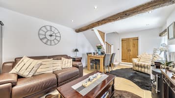 Uma sala de estar moderna com um sofá de couro marrom, uma mesa de centro de madeira e um relógio de parede grande.