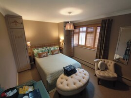 Quarto com cama, poltrona, cômoda e janela com persianas.