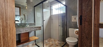Uma casa de banho moderna com chuveiro em cabine de vidro, lavatório de mármore e sanita.
