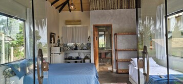 Quarto compacto com cama, mesas de cabeceira, espelho e janela.