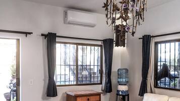 Uma sala de estar com sofá, mesa de centro, poltrona de couro, lustre decorativo e um dispensador de água.