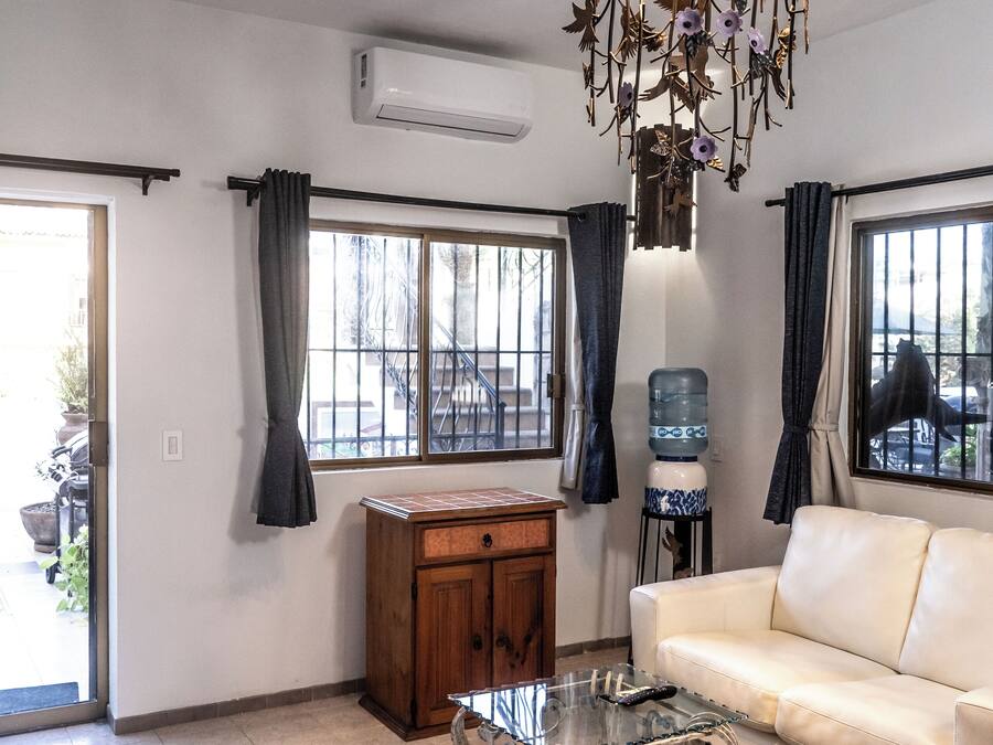 Uma sala de estar com sofá, mesa de centro, poltrona de couro, lustre decorativo e um dispensador de água.