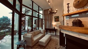 Uma sala de estar moderna com grandes janelas, escada, lustre e lareira.