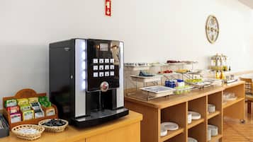 Máquina de café com diversas opções, dispensador de chá e área de buffet com vários alimentos e acompanhamentos.