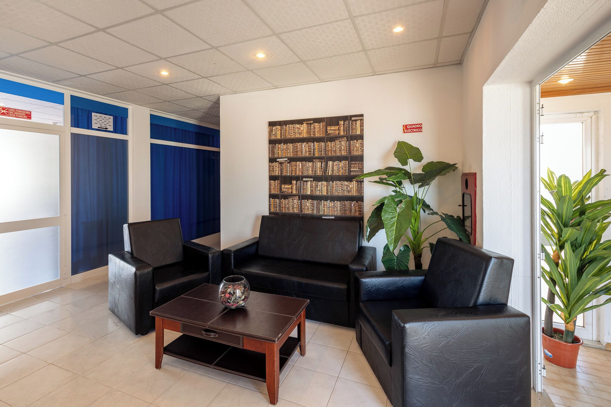 Um hall moderno com um sofá de couro preto, uma mesa de centro de madeira e uma estante.