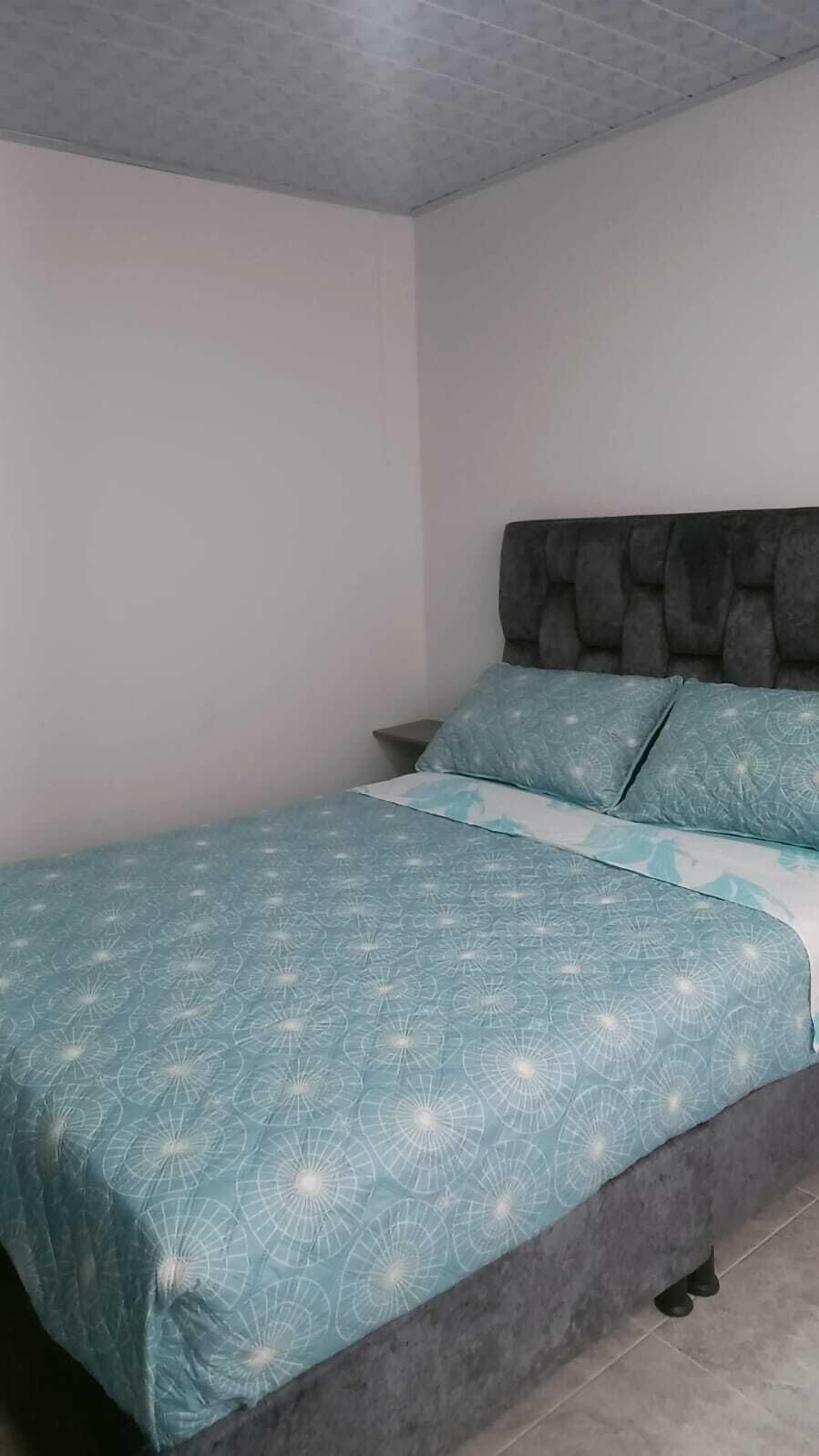Quarto com cama, cabeceira e mesa de cabeceira.