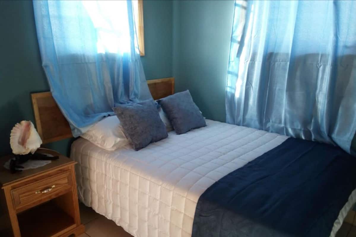 Um quarto com uma cama, uma mesa de cabeceira e uma janela com cortinas.