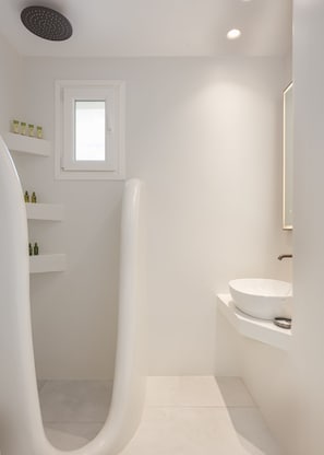Uma casa de banho moderna com uma sanita branca, chuveiro e janela sobre o chuveiro.