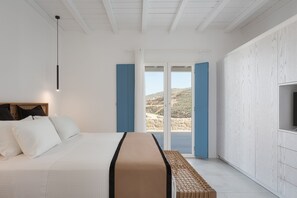 Quarto com cama, um banco, guarda-roupa e vista para o exterior.