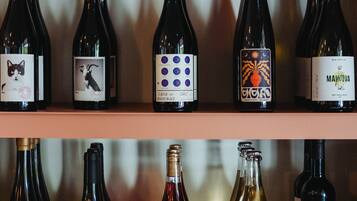 Uma estante de vinhos com diversas garrafas, incluindo algumas com os rótulos 'NINA' e 'MAINOVA'.