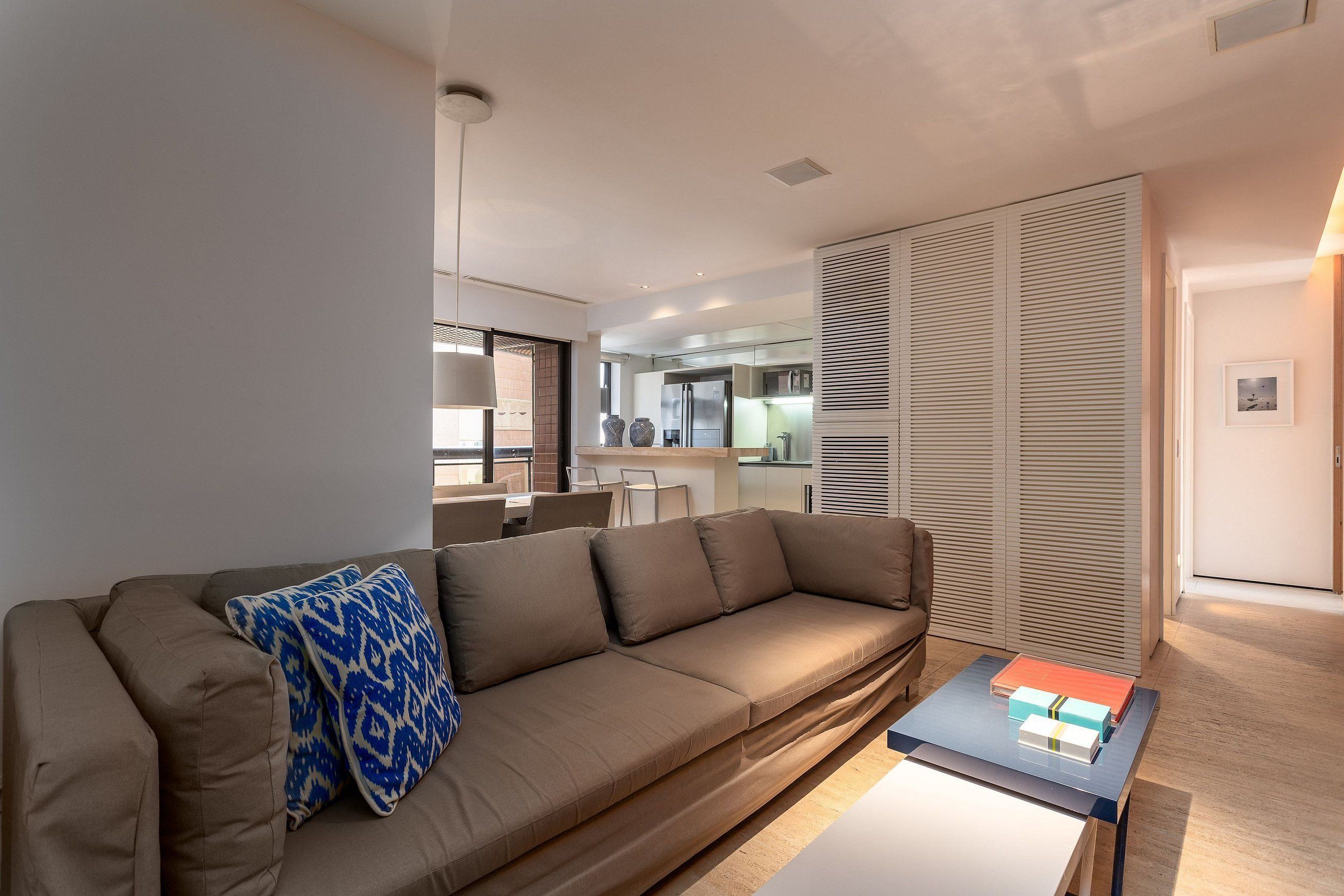 Uma sala de estar moderna com um sofá, uma mesa de centro e vista para a cozinha.