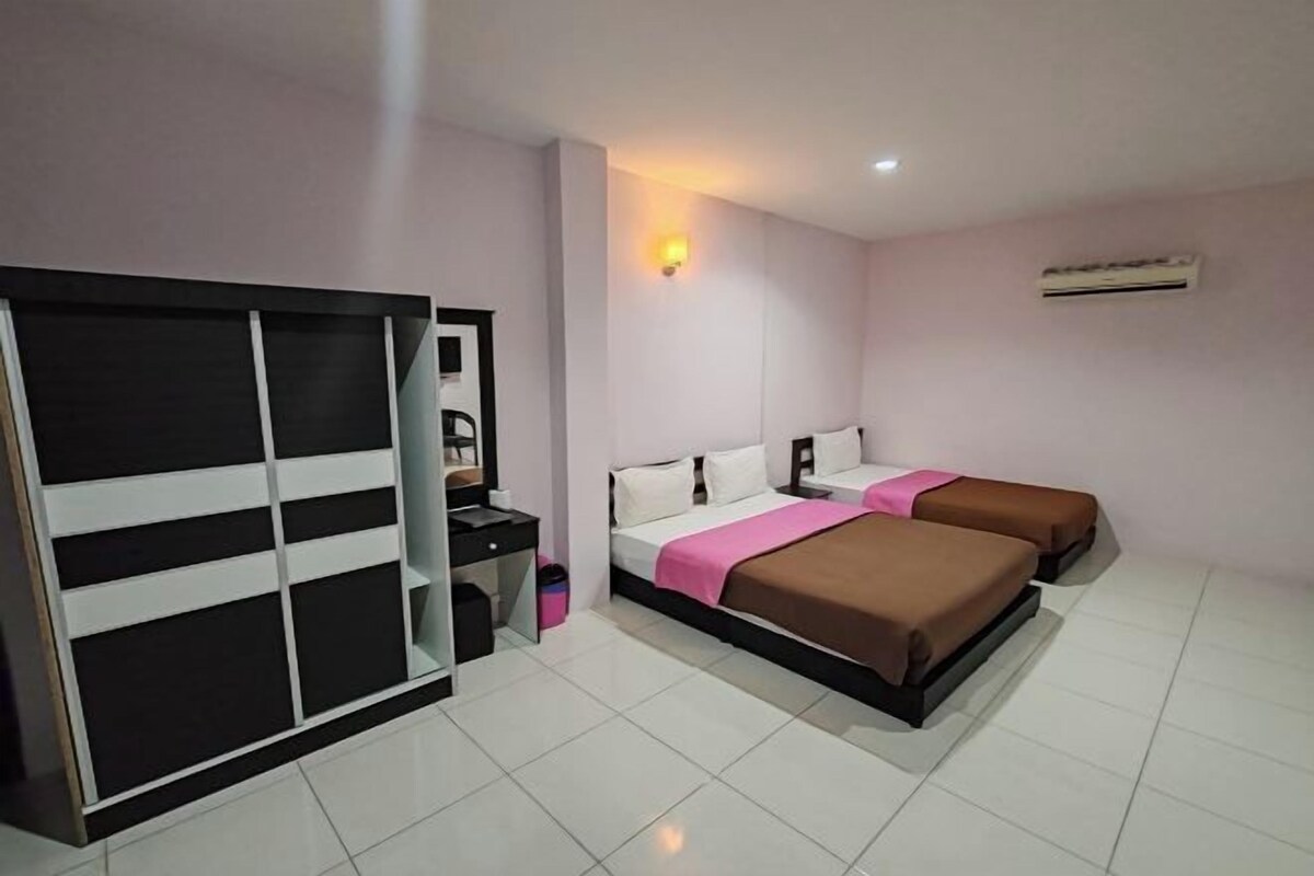 Quarto com duas camas, um guarda-roupa, mesa de cabeceira e ar condicionado.
