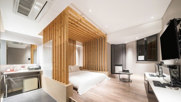 Quarto de hotel moderno com cama, escrivaninha e televisão.
