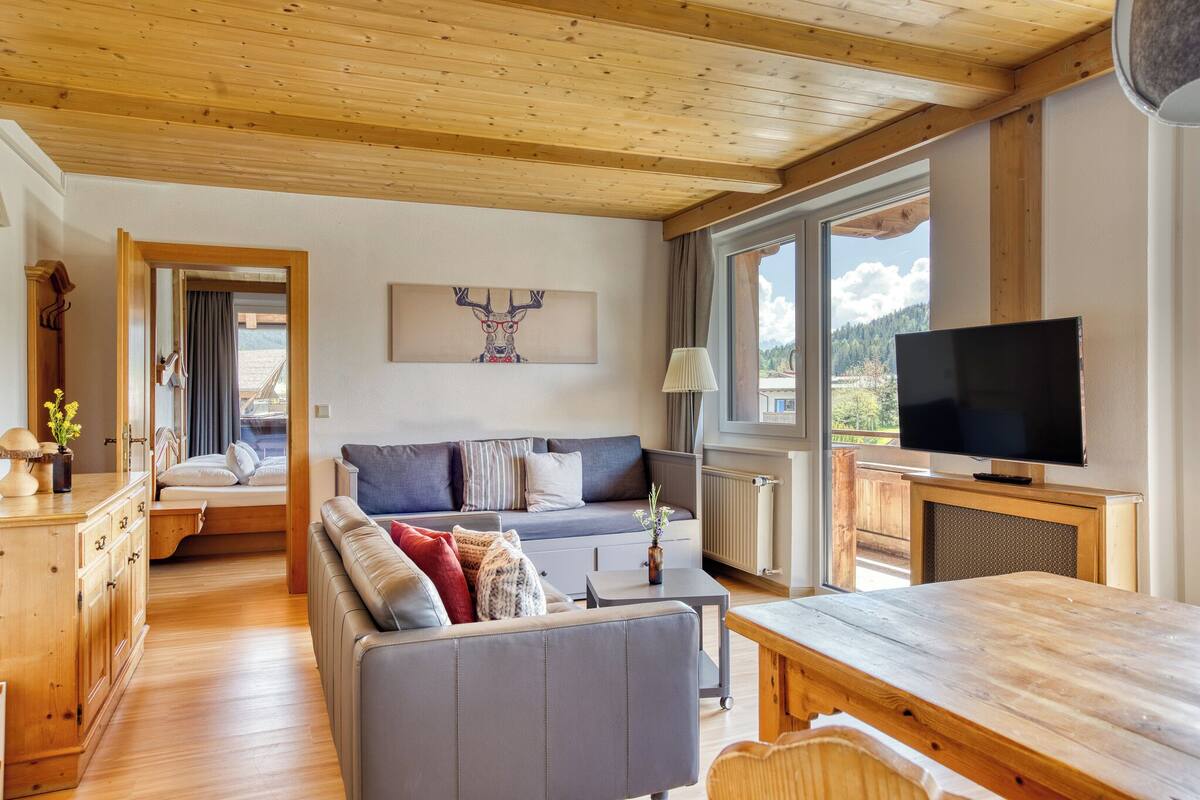 Uma sala de estar aconchegante com um sofá, uma televisão e uma mesa de madeira.