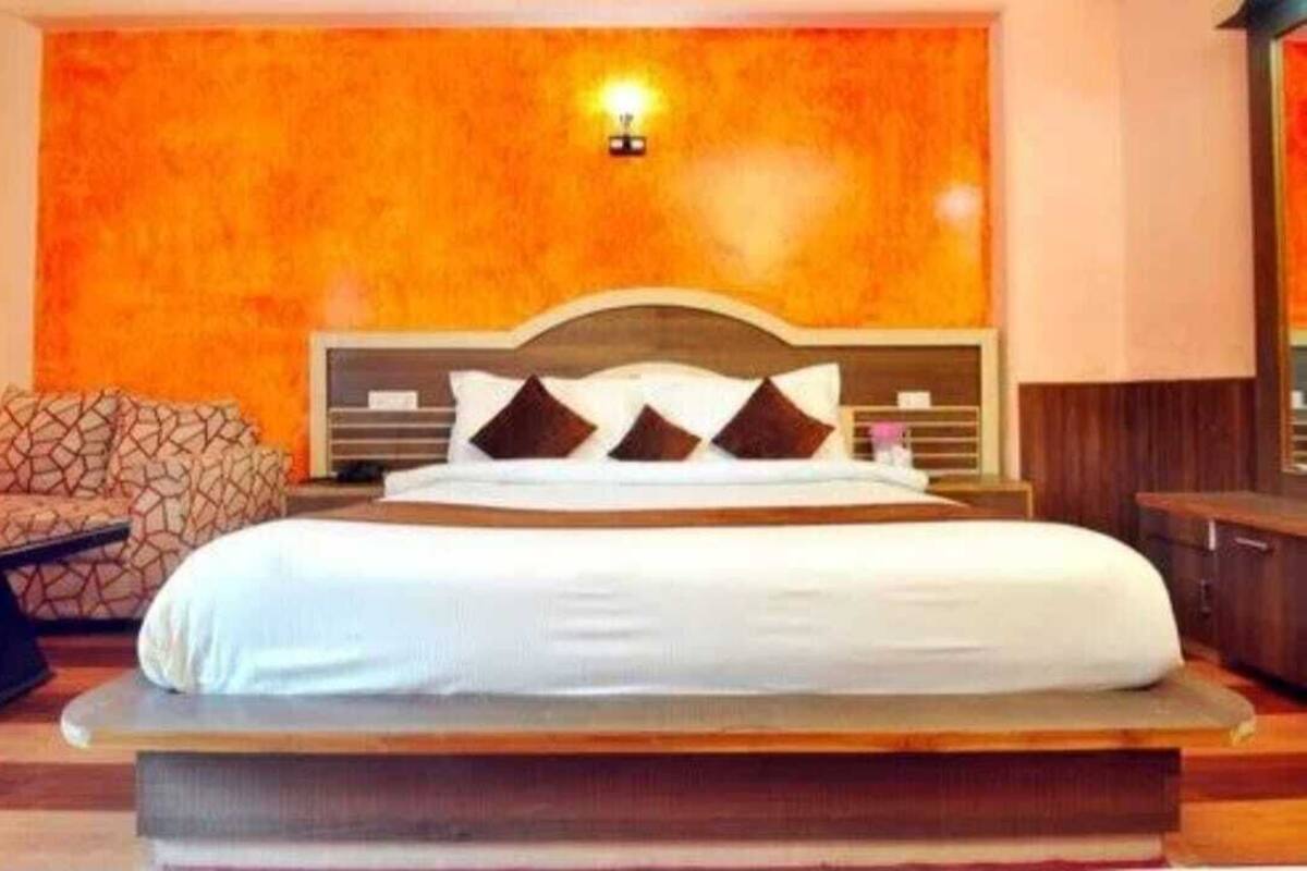 Quarto com uma cama grande, cabeceira e luminária fixada na parede.