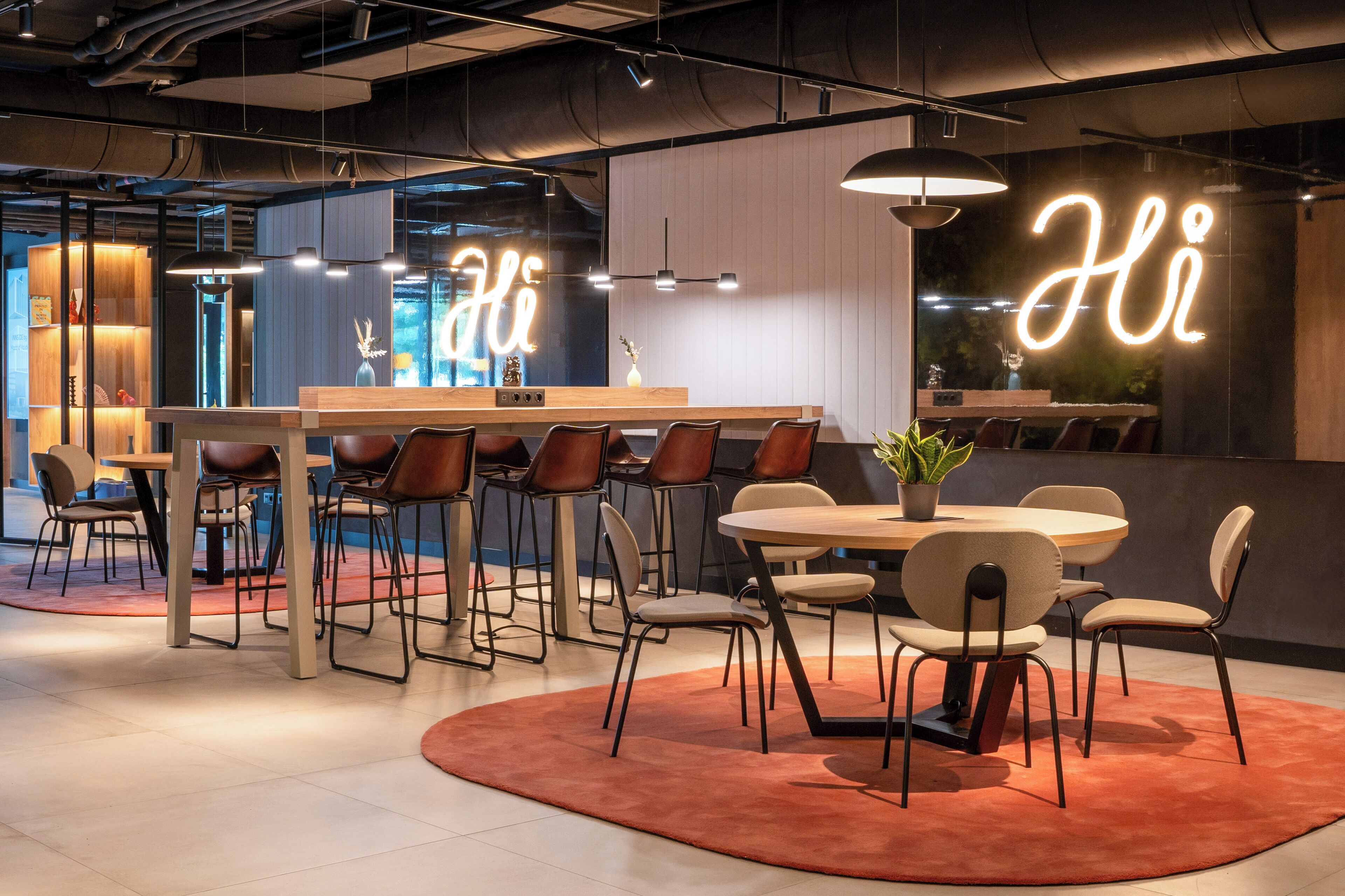 Um interior moderno com área de bar, mesas redondas e banquetas.