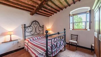 Quarto com cama, cadeira, janela e abajur.