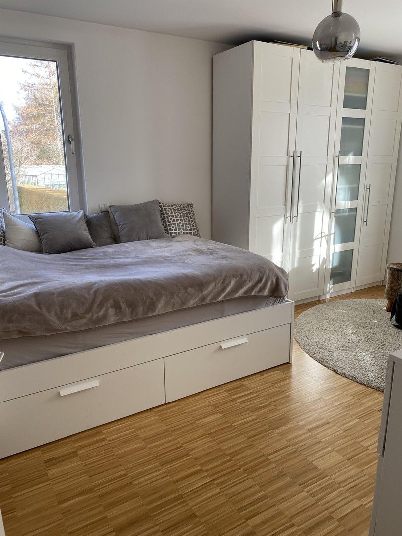 Quarto com cama, guarda-roupa e janela.