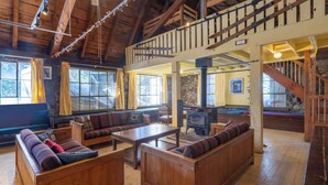 Interior acolhedor de uma cabana com móveis de madeira, lareira e um mezanino.