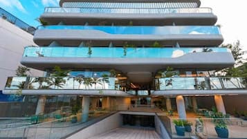 Edifício com vários andares, varandas, área de estar externa e plantas em vasos.