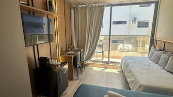 Quarto de hotel com cama, escrivaninha, televisão e vista da cidade.