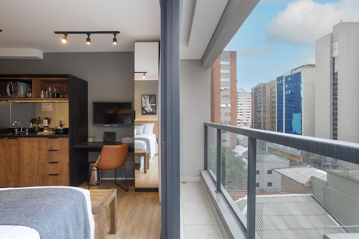 Um apartamento moderno com cozinha, área de jantar e varanda com vista para a cidade.