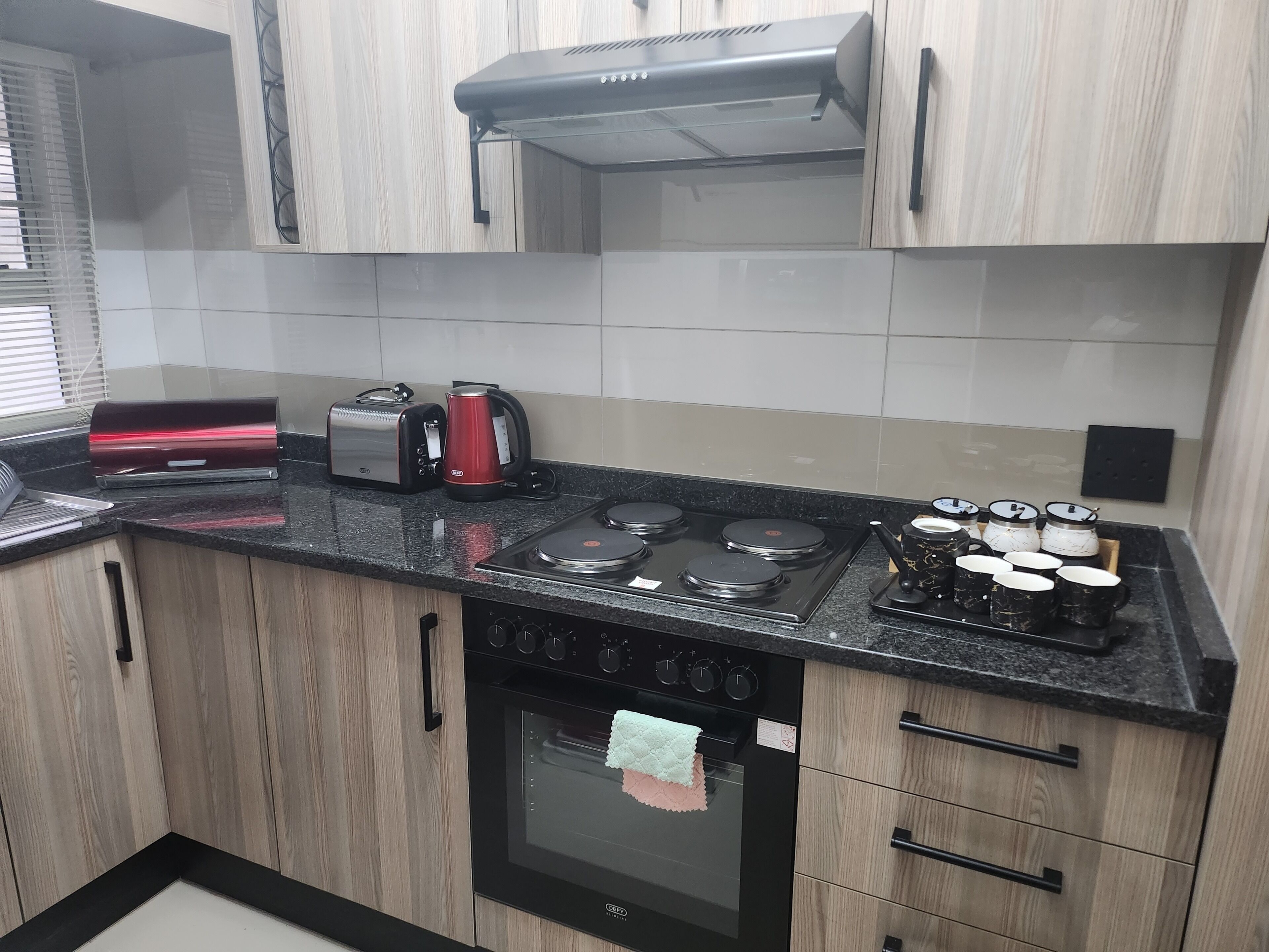 Uma cozinha equipada com fogão, forno, torradeira, chaleira e exaustor.