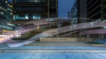 Um edifício moderno com janelas de vidro refletivas e um caminho de pedra que leva a uma placa.