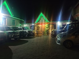 Um hotel com entrada iluminada em verde e vários carros estacionados.