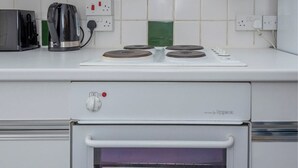 Uma cozinha com forno embutido, torradeira e chaleira.