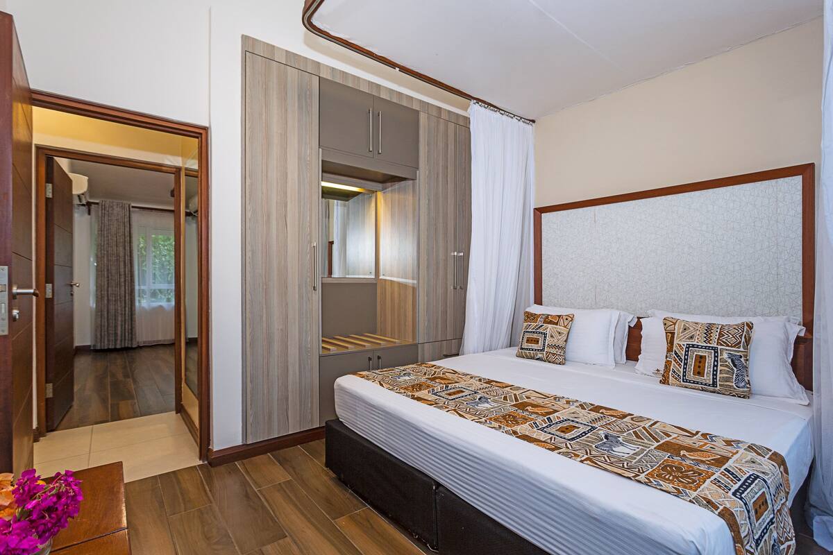 Quarto com uma cama grande, um guarda-roupa e um espelho.